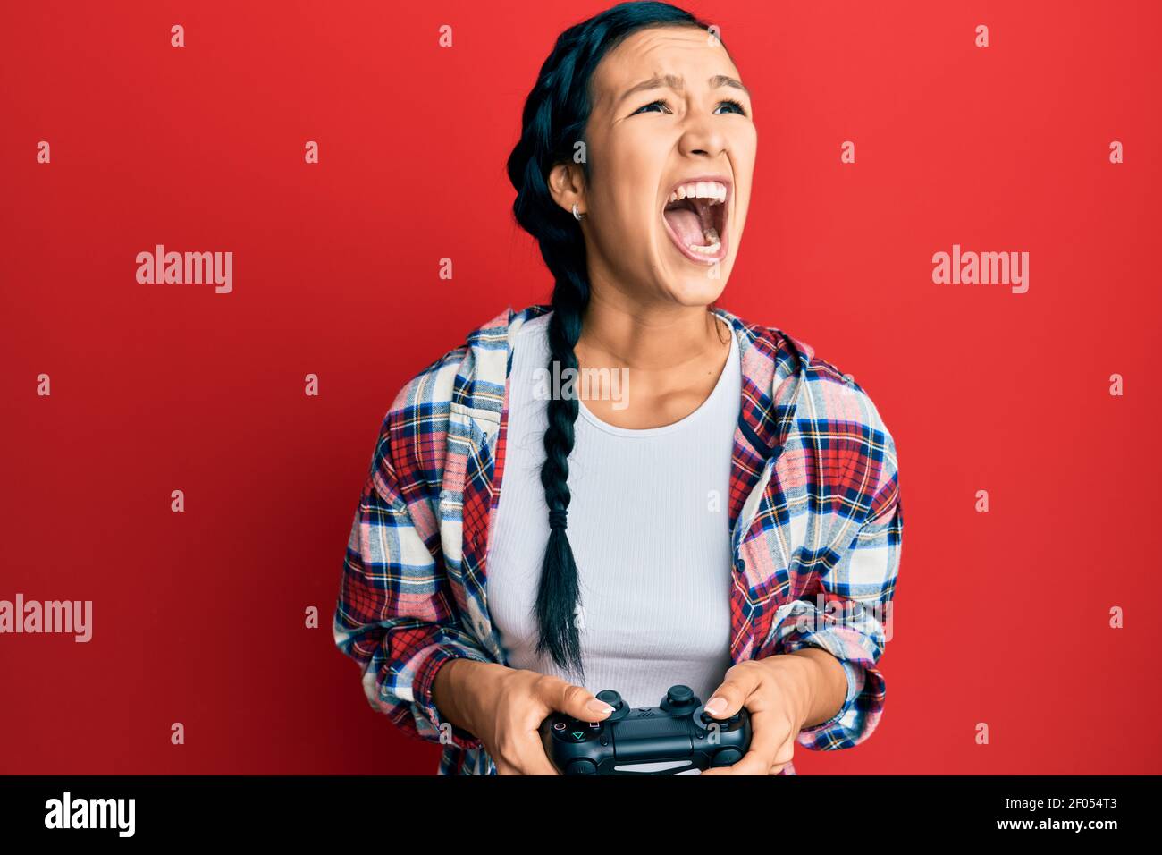 Beautiful hispanic woman playing video game holding controller angry ...