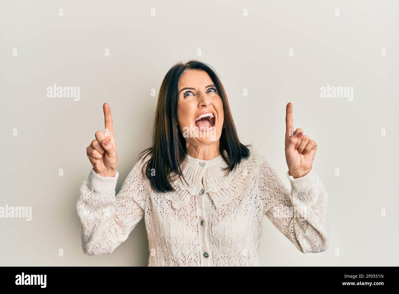 Middle age brunette woman pointing up with fingers angry and mad ...