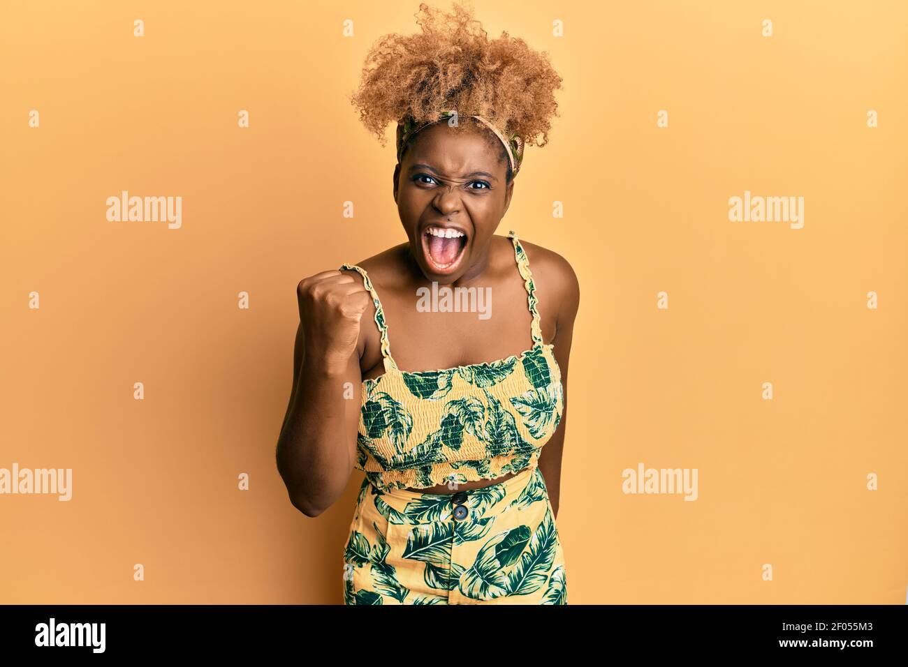 Young african woman with afro hair wearing summer dress angry and mad ...
