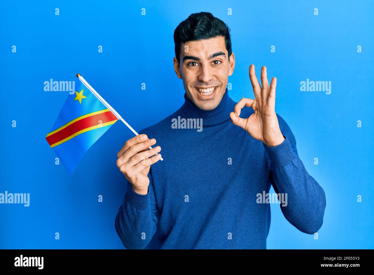 Handsome hispanic man holding democratic republic of the congo flag ...