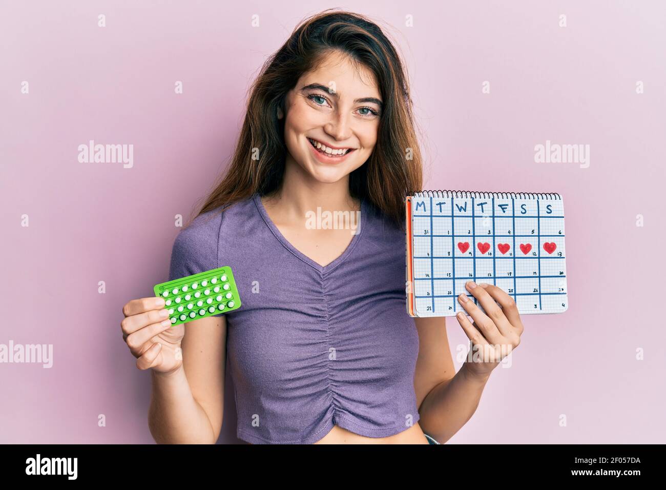 Young caucasian woman holding birth control pills and menstrual ...