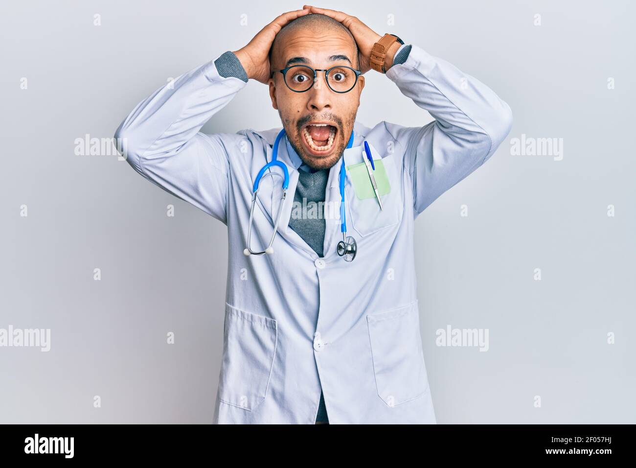 Hispanic adult man wearing doctor uniform and stethoscope crazy and ...