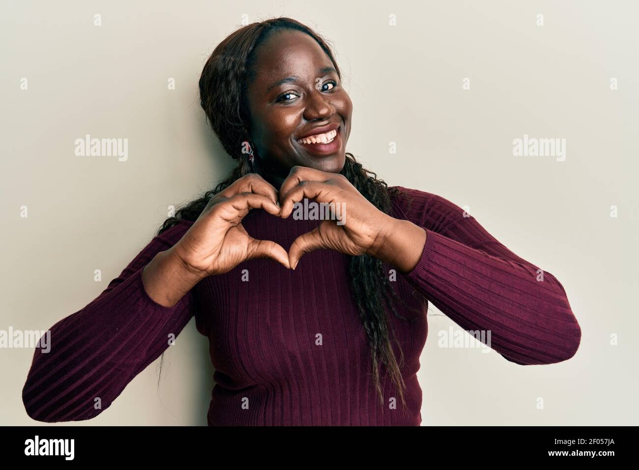 African young woman wearing casual clothes smiling in love doing heart ...