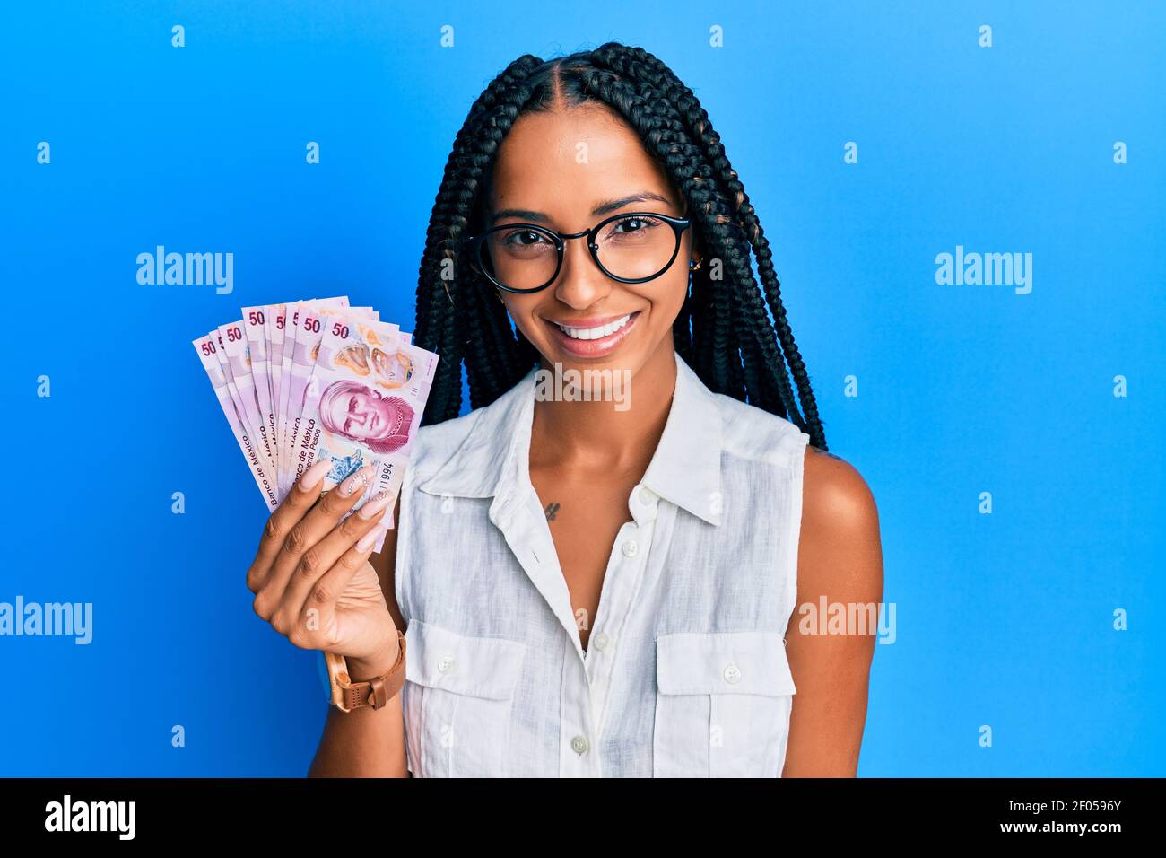 Beautiful hispanic woman holding 50 mexican pesos banknotes looking ...