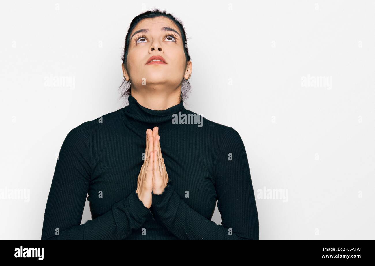 Young hispanic woman wearing casual clothes begging and praying with ...