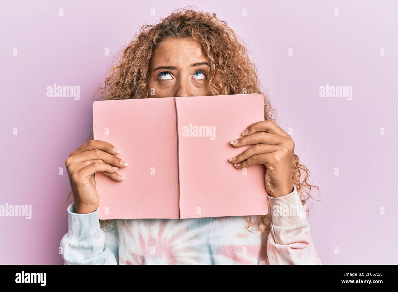 Beautiful caucasian teenager girl reading a book covering face angry ...