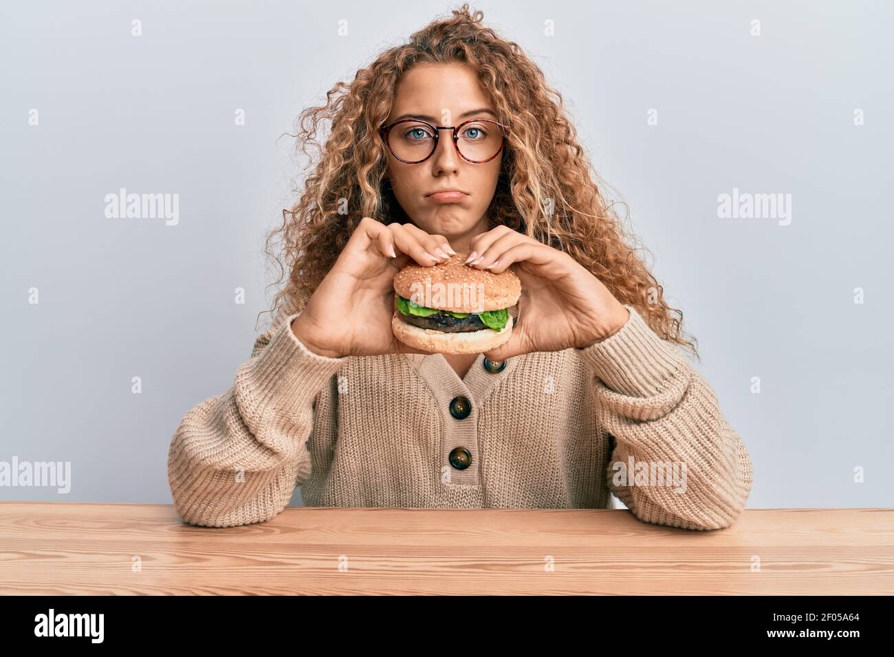 Beautiful caucasian teenager girl eating a tasty classic burger ...
