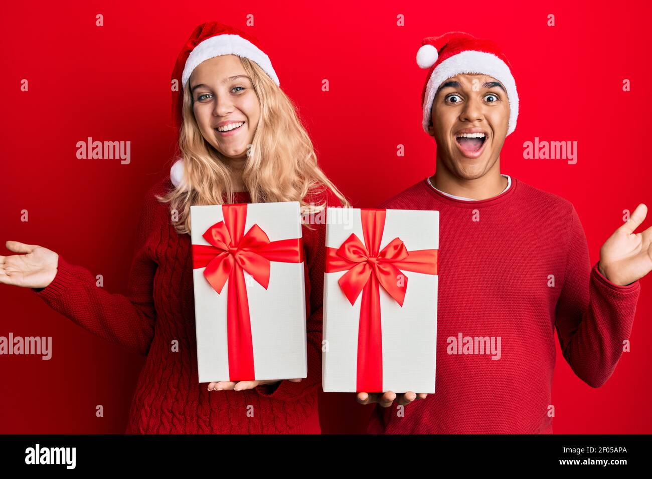 Young interracial couple wearing christmas hat and holding a gift ...