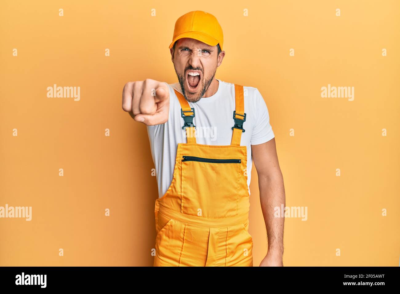 Young handsome man wearing handyman uniform over yellow background ...