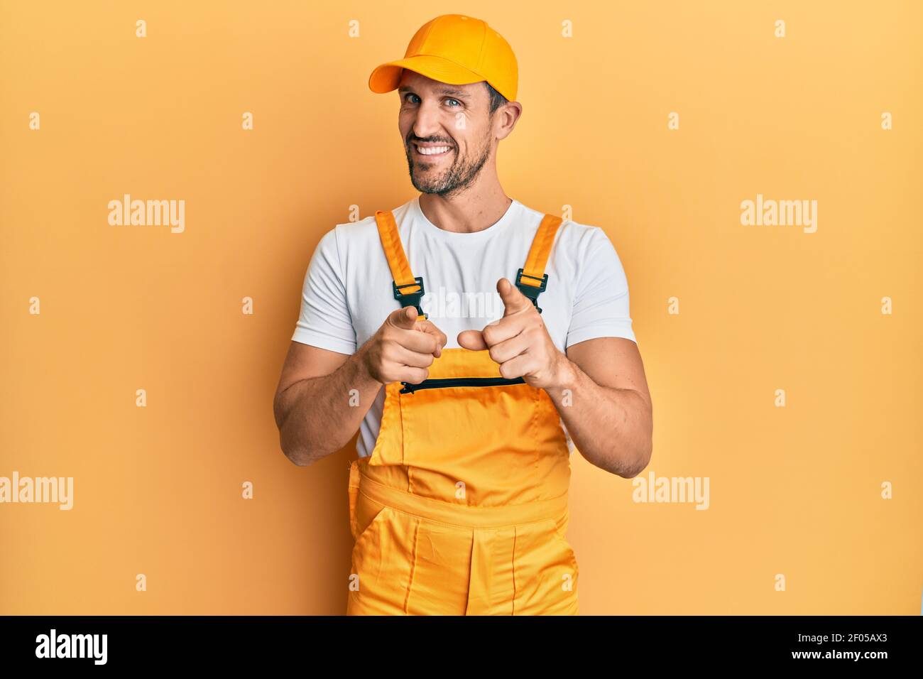 Young handsome man wearing handyman uniform over yellow background ...