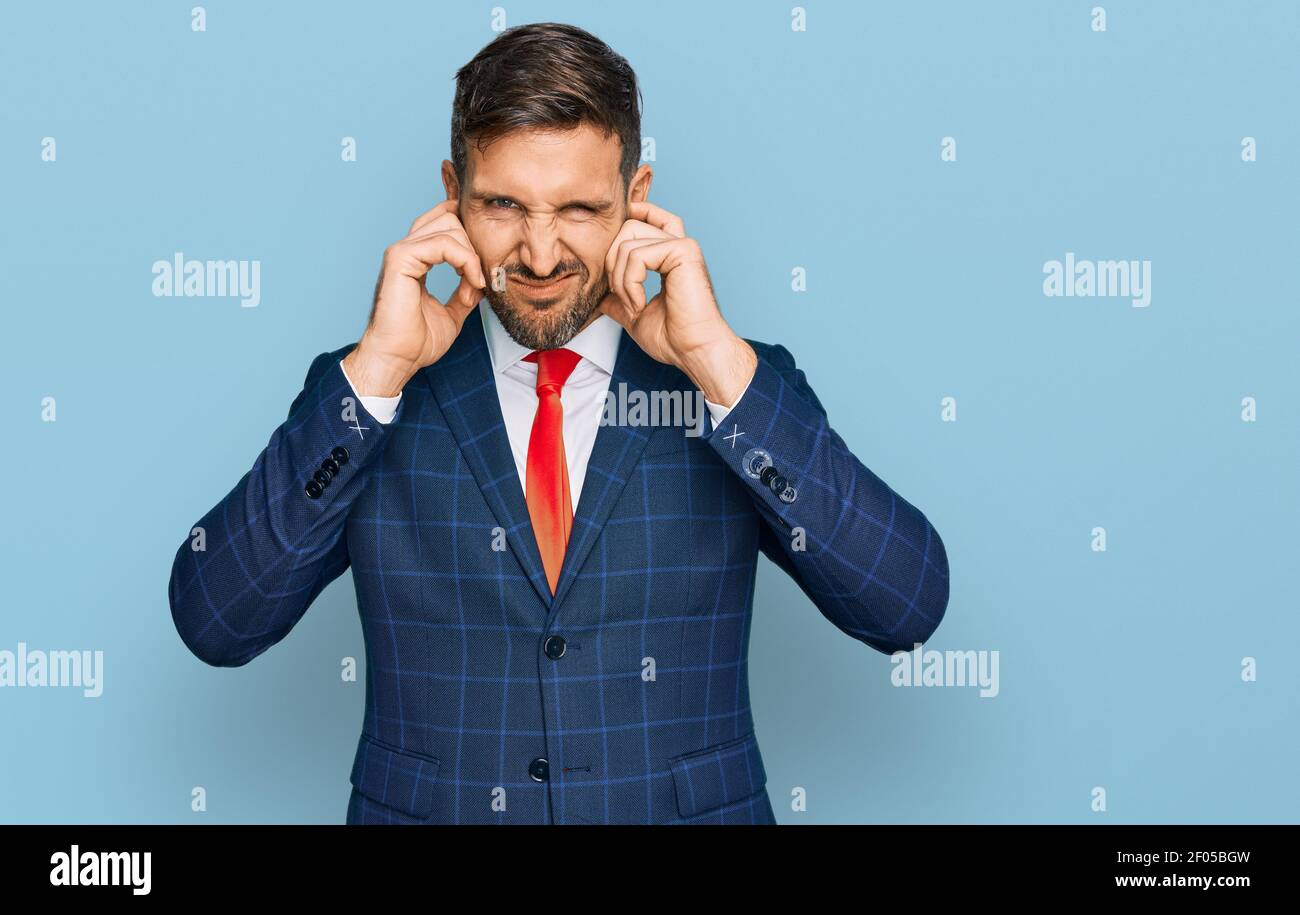 Handsome man with beard wearing business suit and tie covering ears ...
