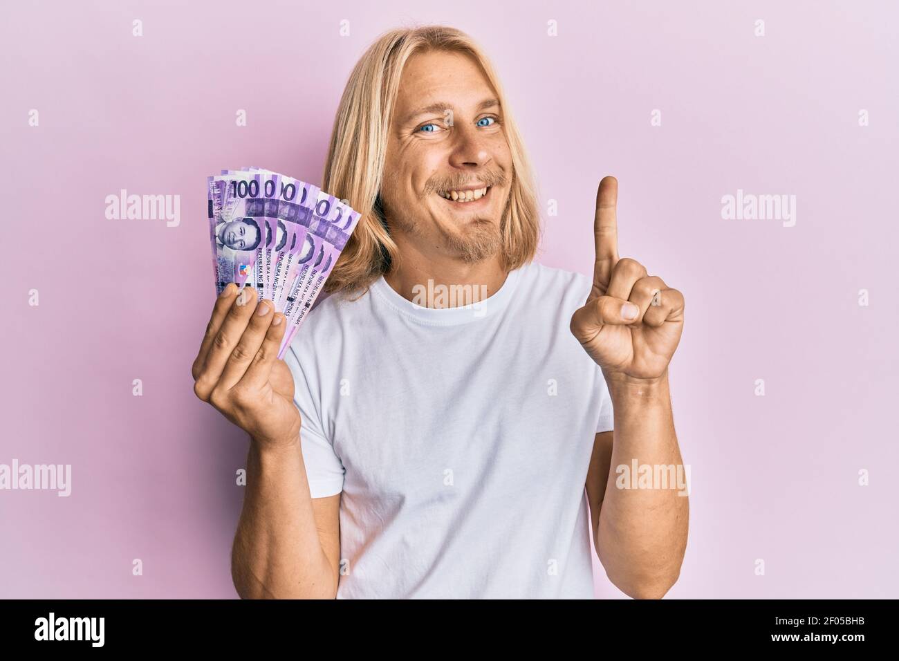Caucasian young man with long hair holding 100 philippine peso ...