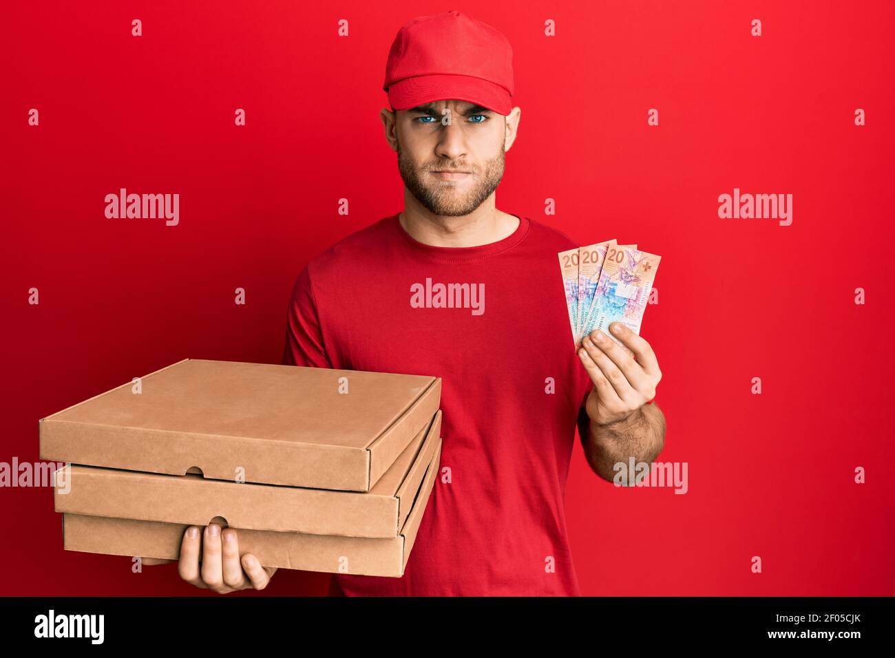 Young caucasian man holding delivery box and swiss franc banknotes ...