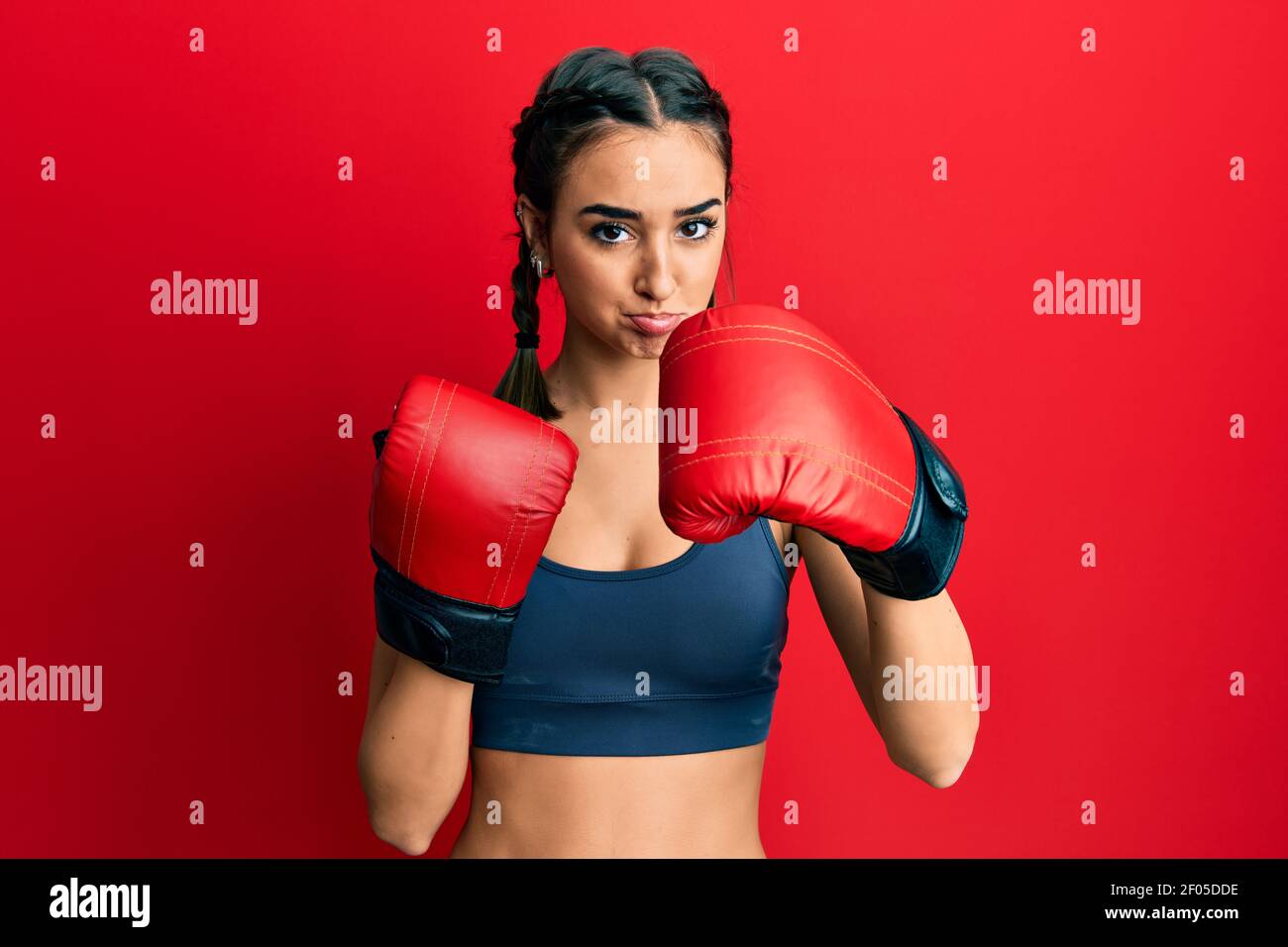 Young brunette girl using boxing gloves depressed and worry for ...