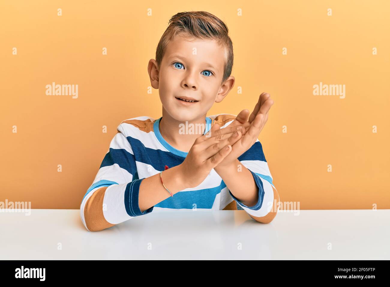 Adorable caucasian kid wearing casual clothes sitting on the table ...