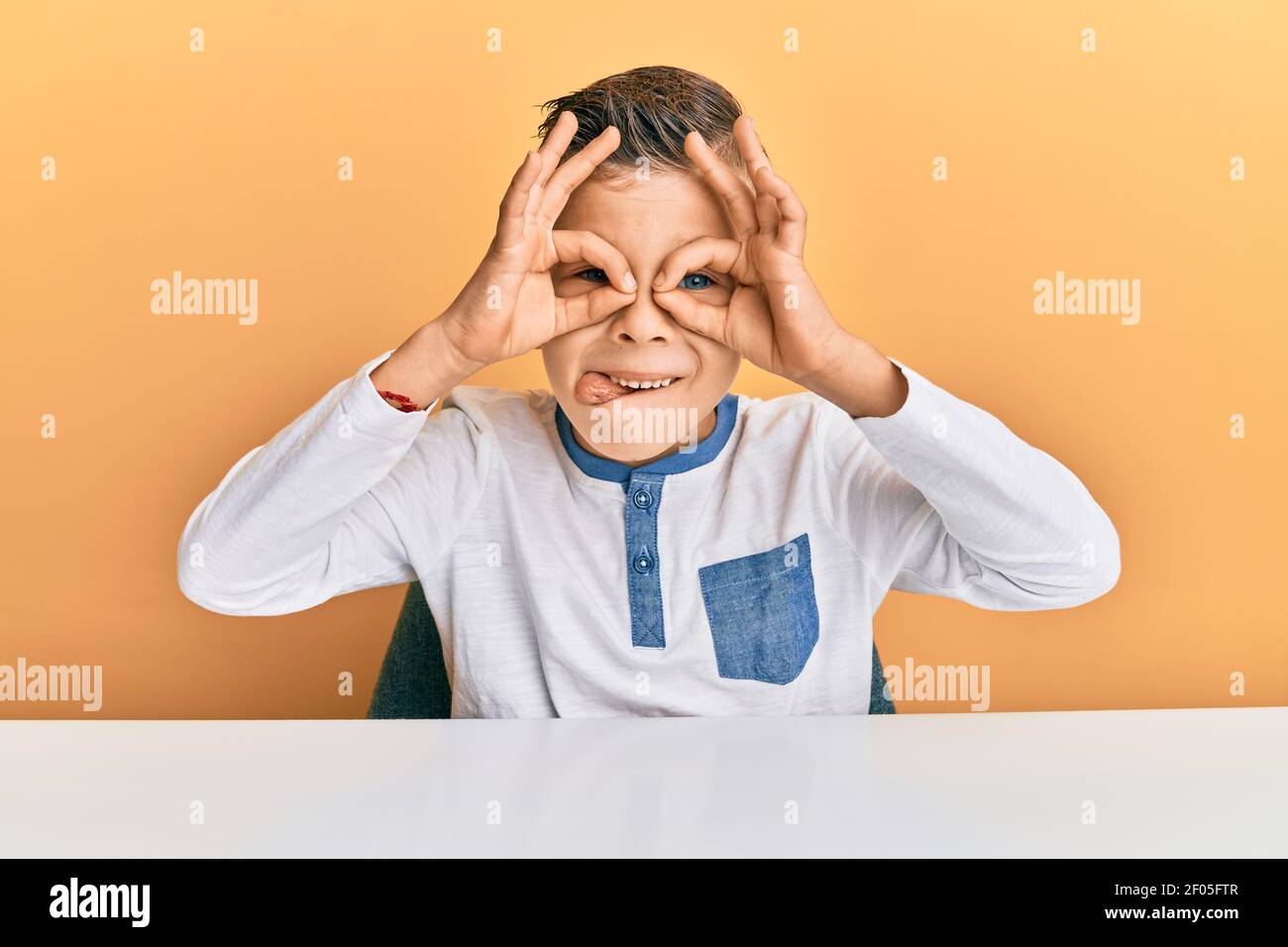Adorable caucasian kid wearing casual clothes sitting on the table ...