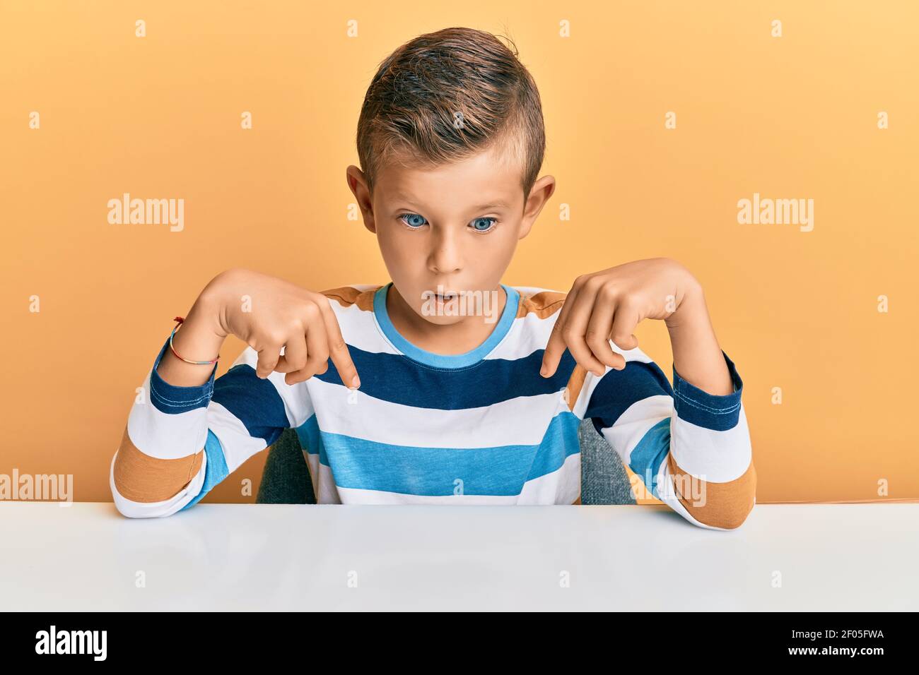 Adorable caucasian kid wearing casual clothes sitting on the table ...