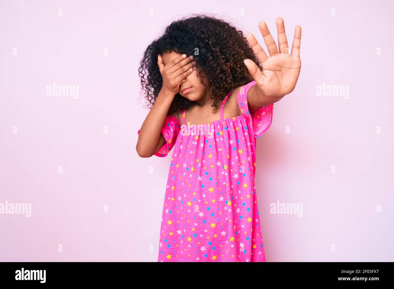 African american child with curly hair wearing casual dress covering ...