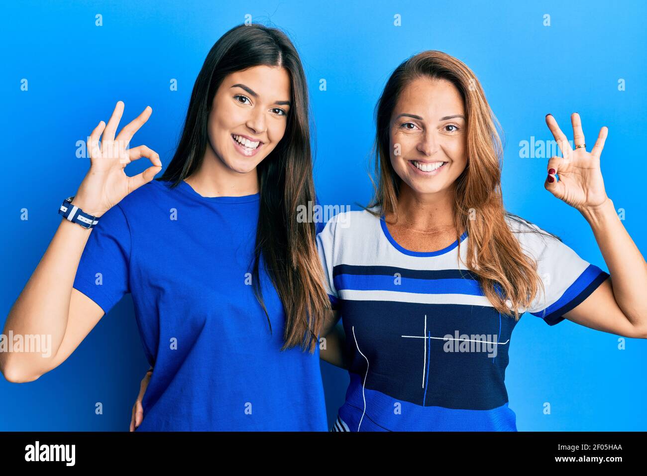 Hispanic family of mother and daughter wearing casual clothes over blue ...