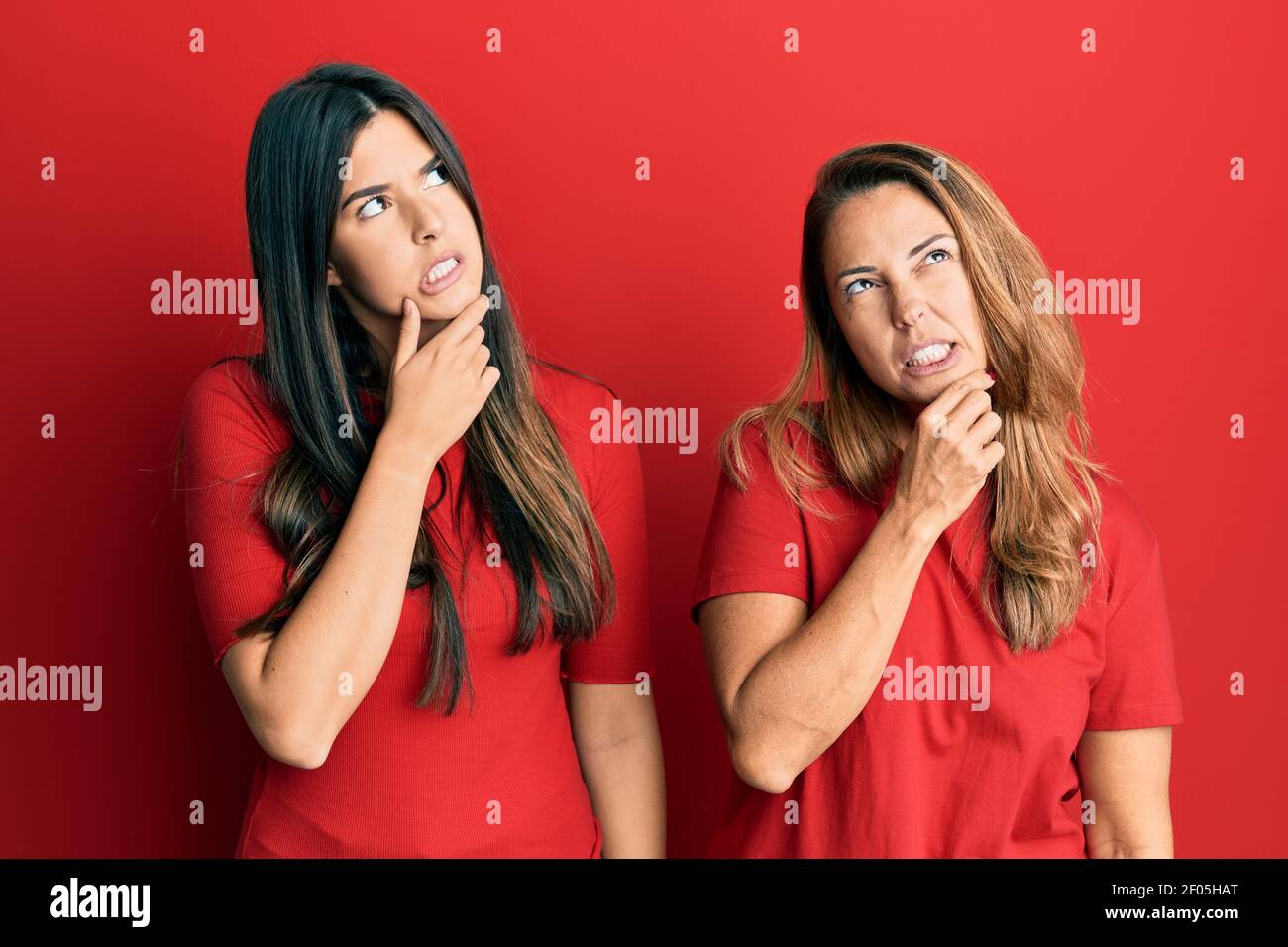 Hispanic family of mother and daughter wearing casual clothes over red ...