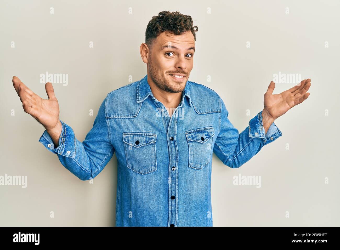 Young hispanic man wearing casual clothes clueless and confused with ...