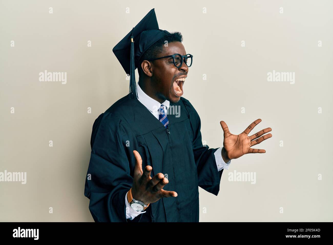 Handsome black man wearing graduation cap and ceremony robe celebrating ...