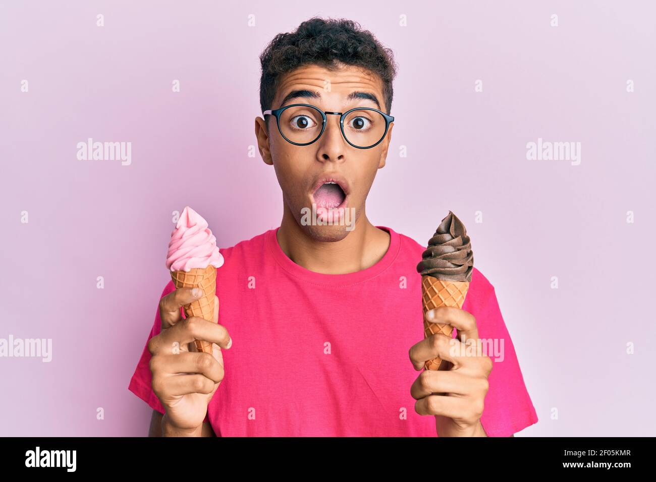 Young handsome african american man holding ice cream cones afraid and ...