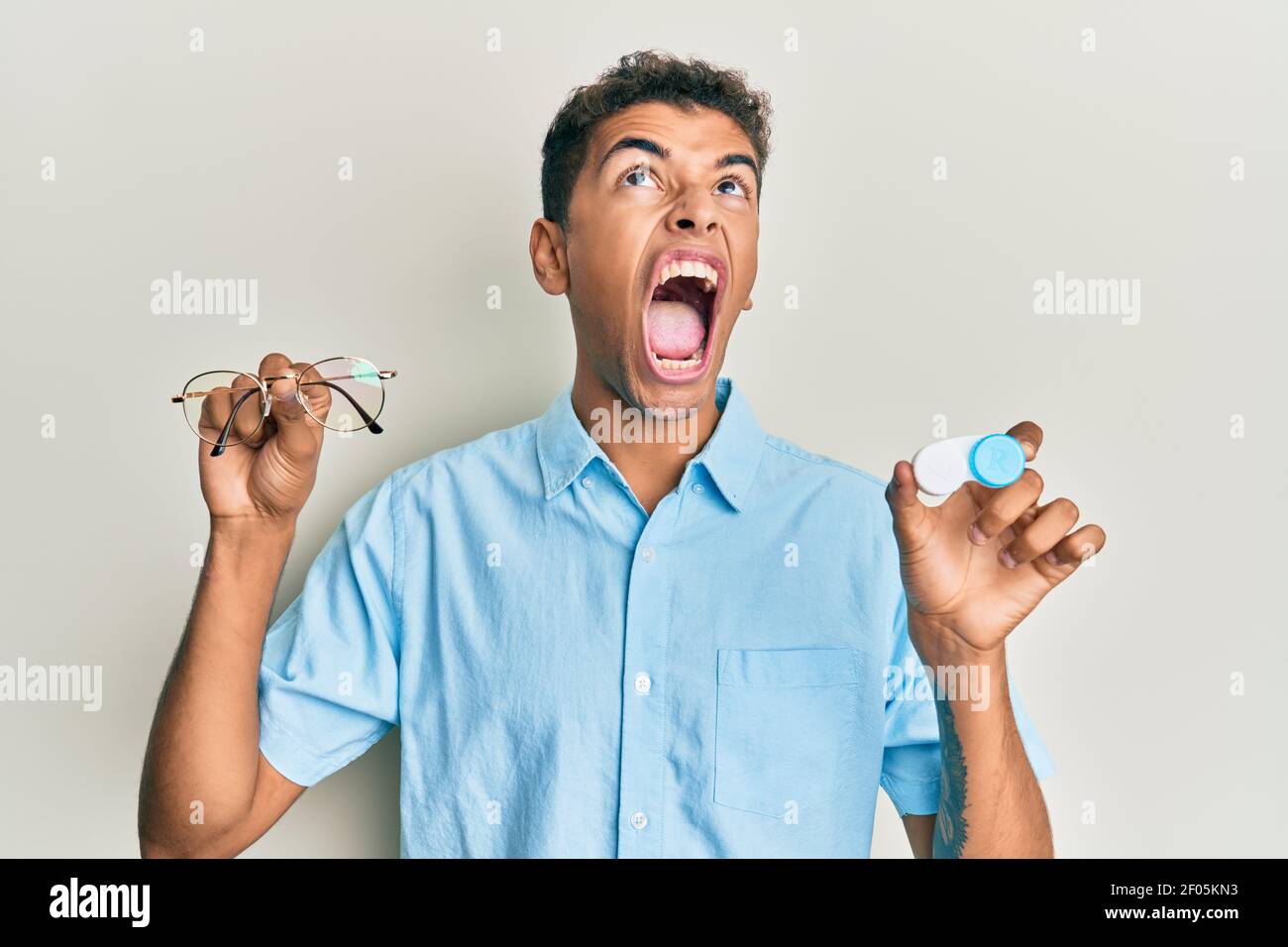 Young handsome african american man holding glasses and contact lenses ...