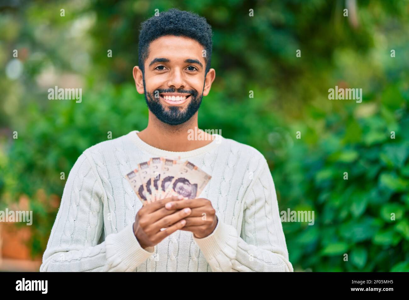 Young african american man smiling happy holding mexican 500 pesos ...