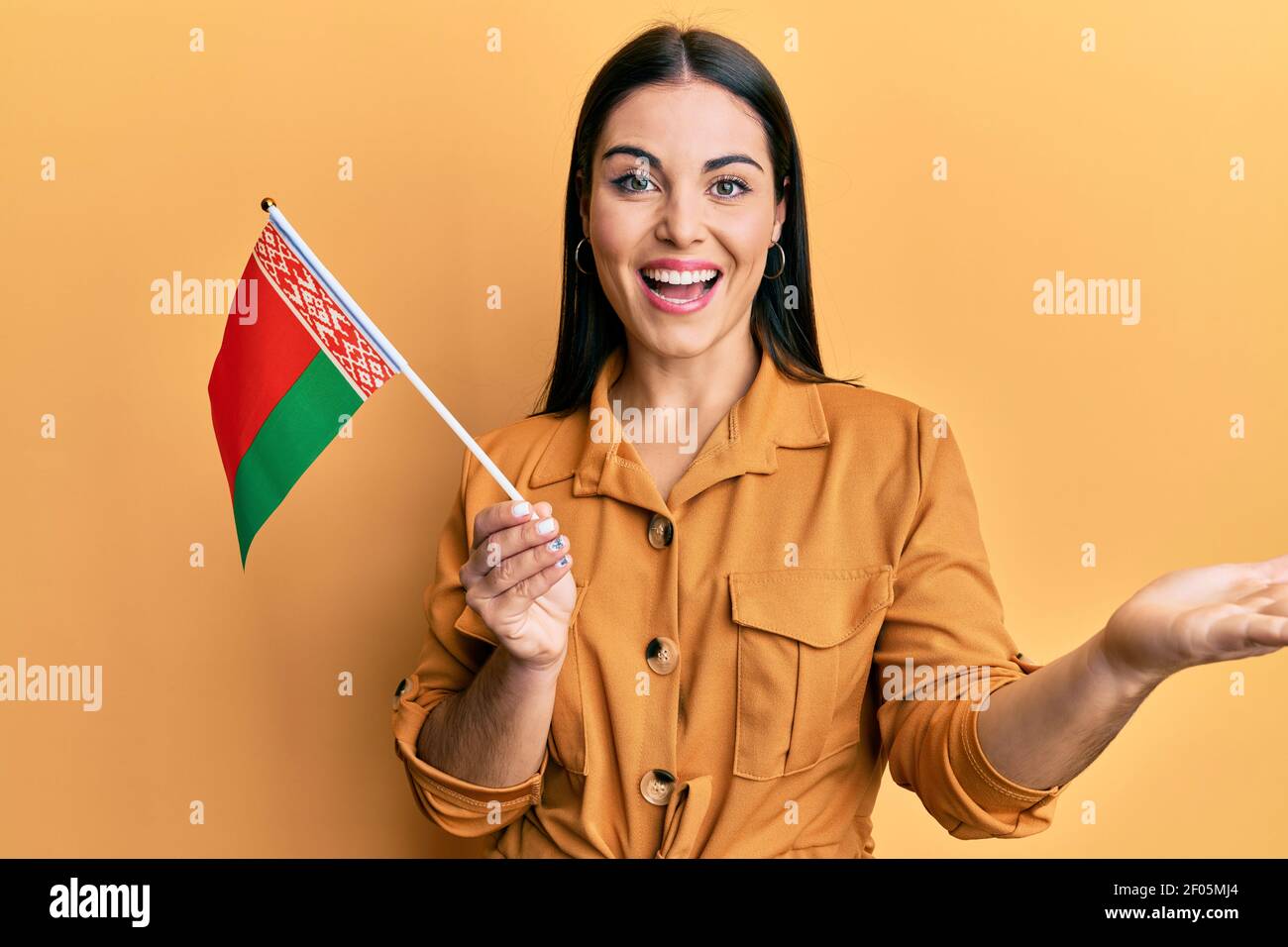 Young brunette woman holding belarus flag celebrating achievement with ...