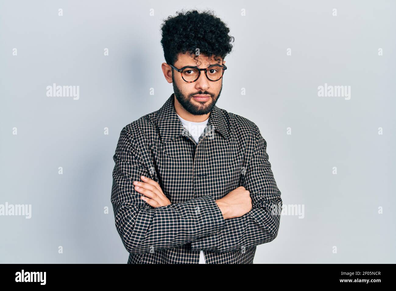 Young arab man with beard wearing glasses with arms crossed gesture ...