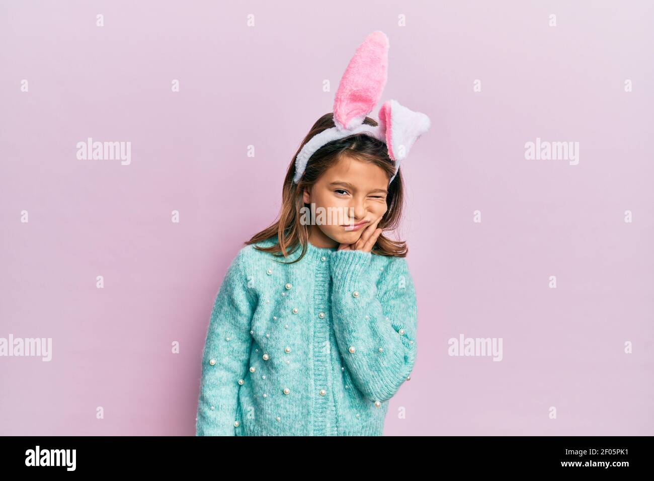 Little beautiful girl wearing cute easter bunny ears touching mouth ...