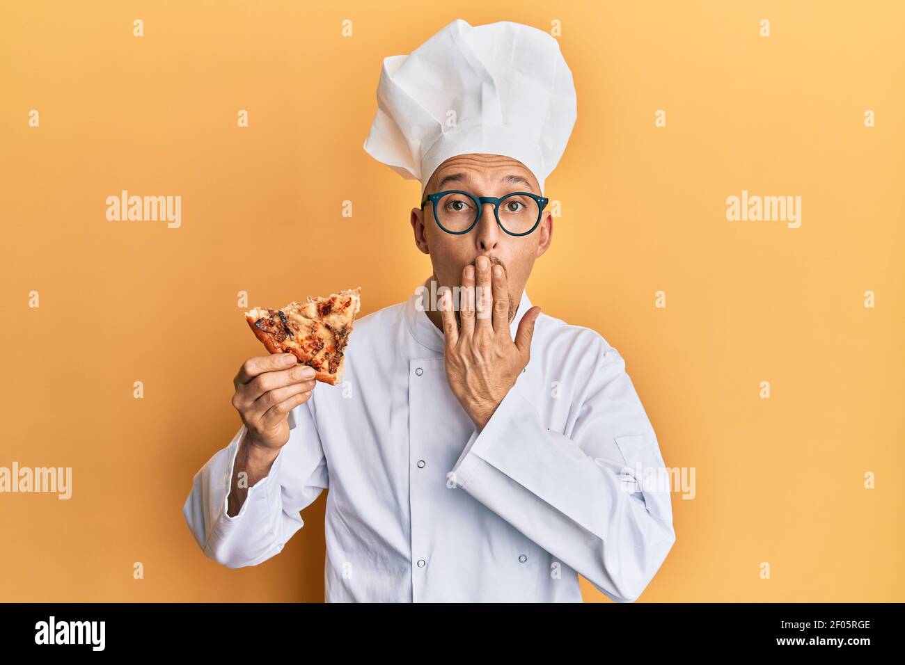 Bald man with beard wearing professional cook apron holding italian ...