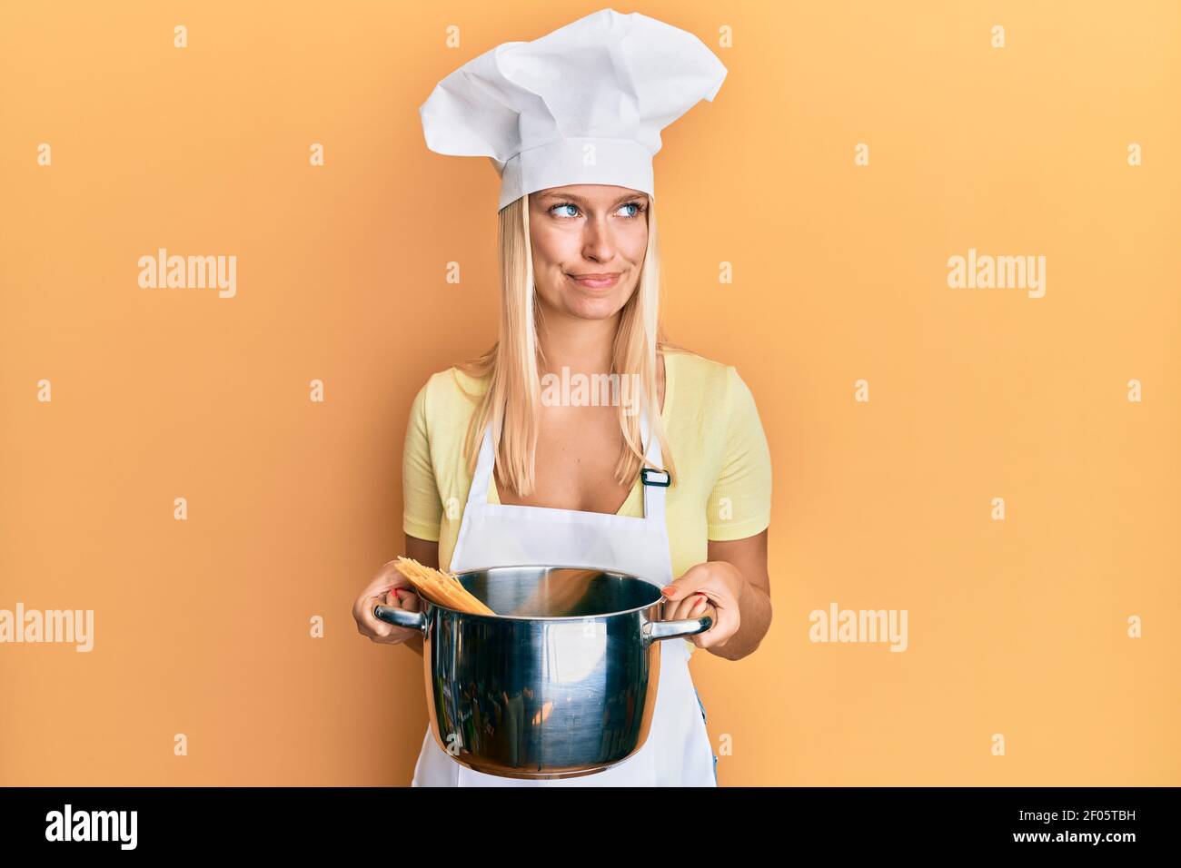 Young blonde girl cooking spaghetti smiling looking to the side and ...