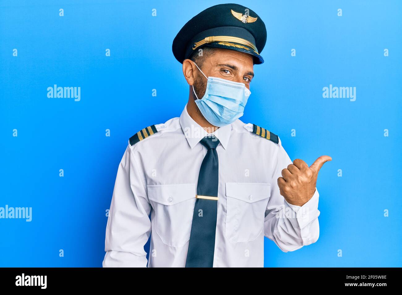 Handsome man with beard wearing airplane pilot uniform wearing safety ...