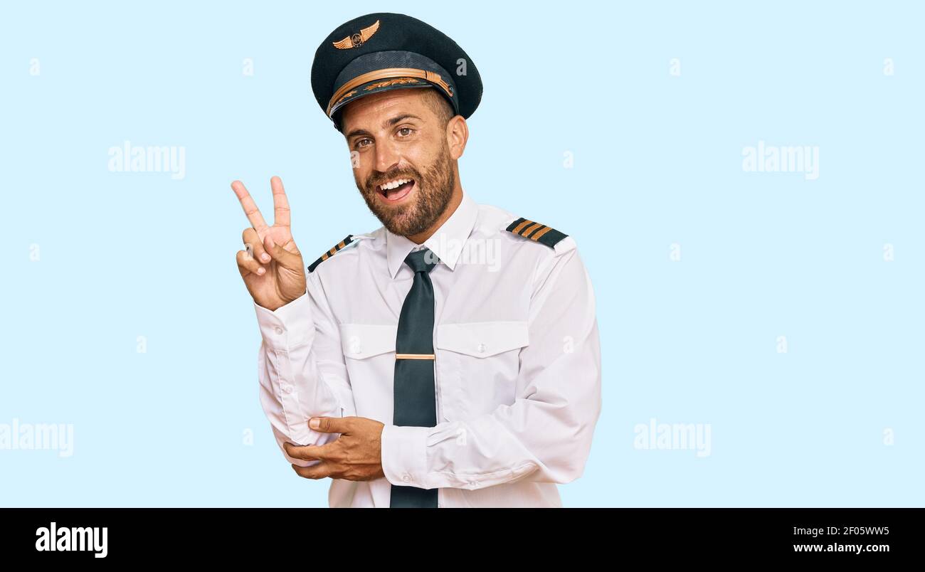 Handsome man with beard wearing airplane pilot uniform smiling with ...