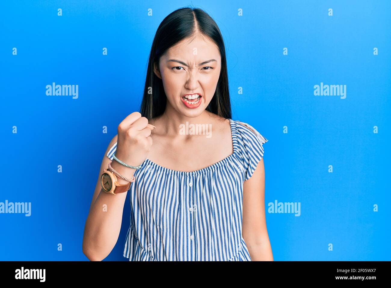 Young chinese woman wearing casual striped t-shirt angry and mad ...