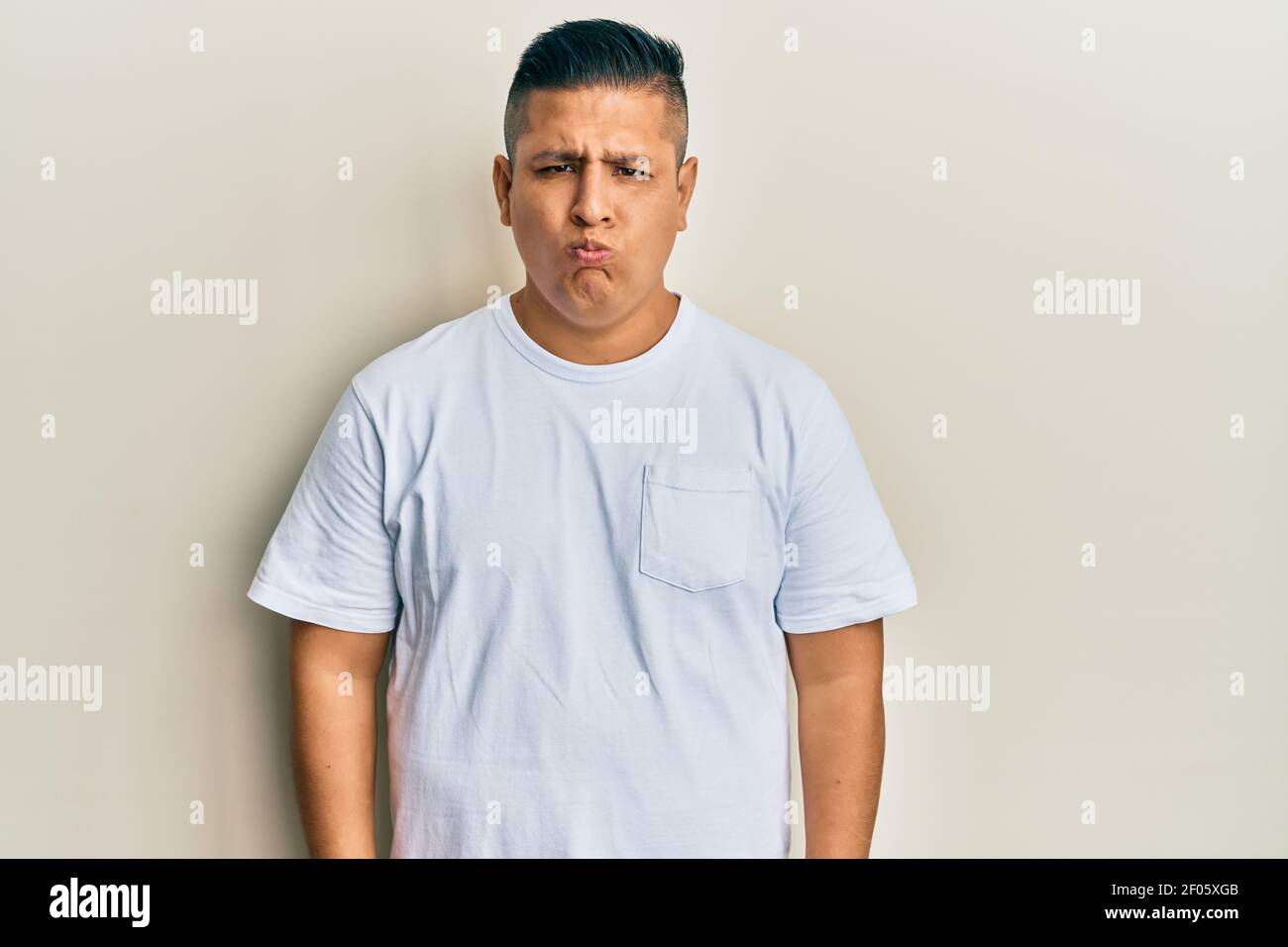Young latin man wearing casual white t shirt depressed and worry for ...