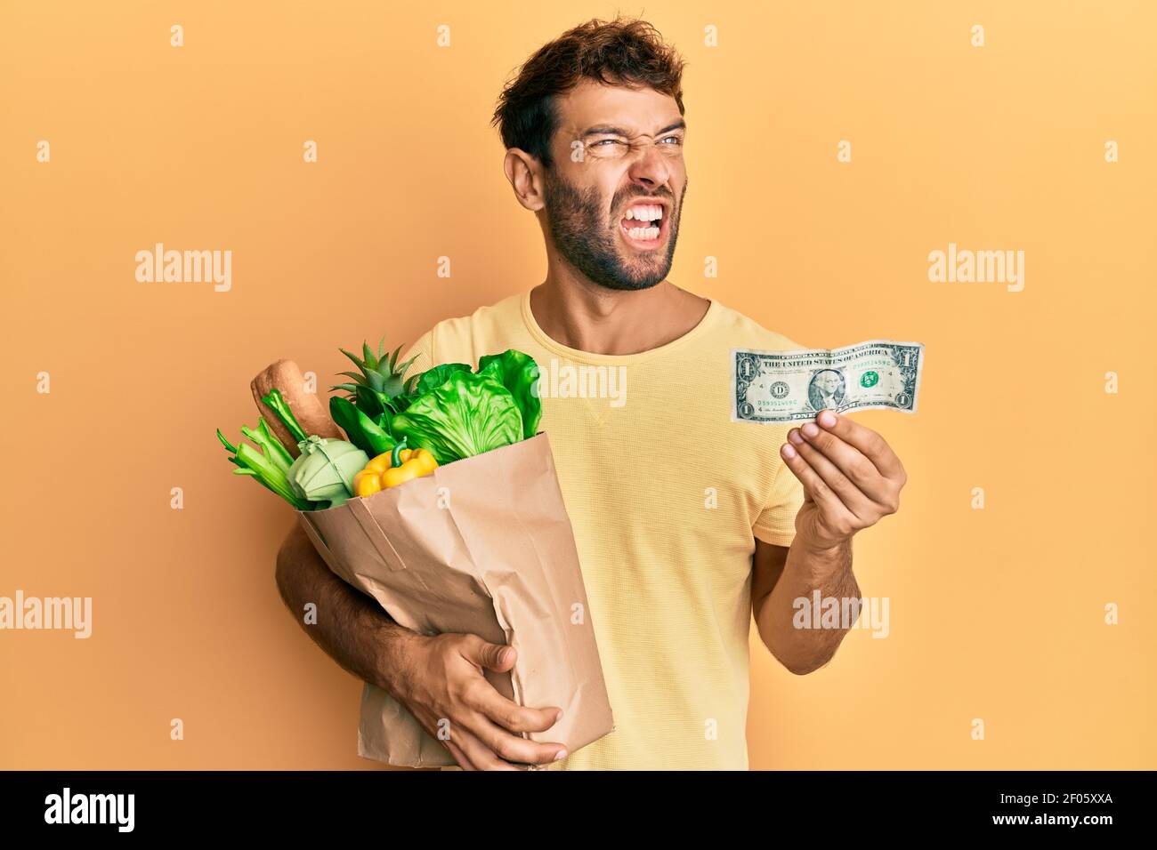 Handsome man with beard holding groceries and 1 american dollar ...