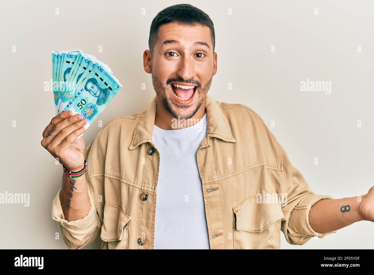 Handsome man with tattoos holding 50 yuan chinese banknotes celebrating ...