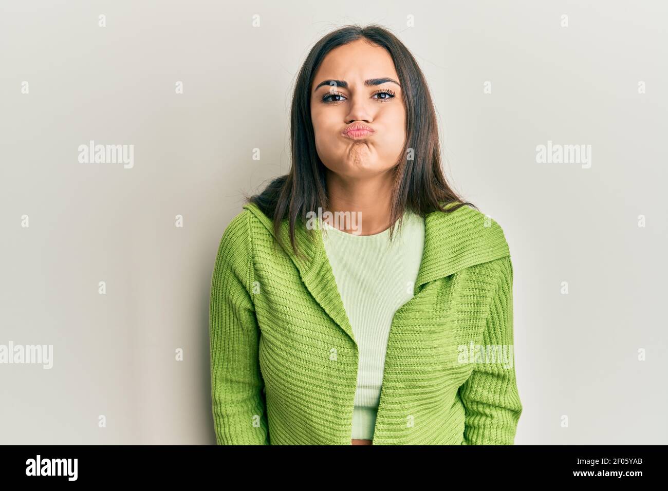 Young brunette woman wearing casual clothes puffing cheeks with funny ...