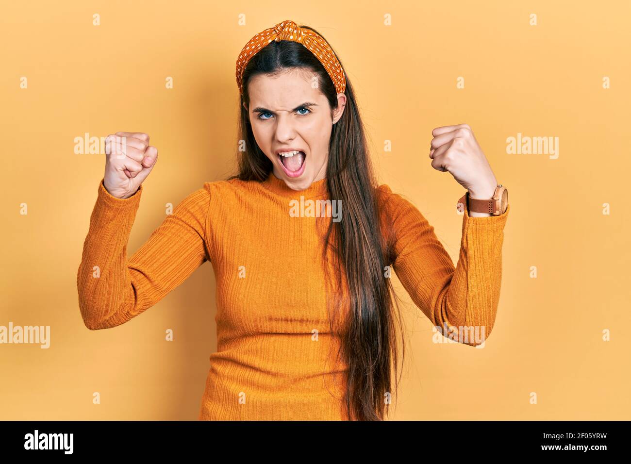 Young brunette teenager wearing casual yellow sweater angry and mad ...
