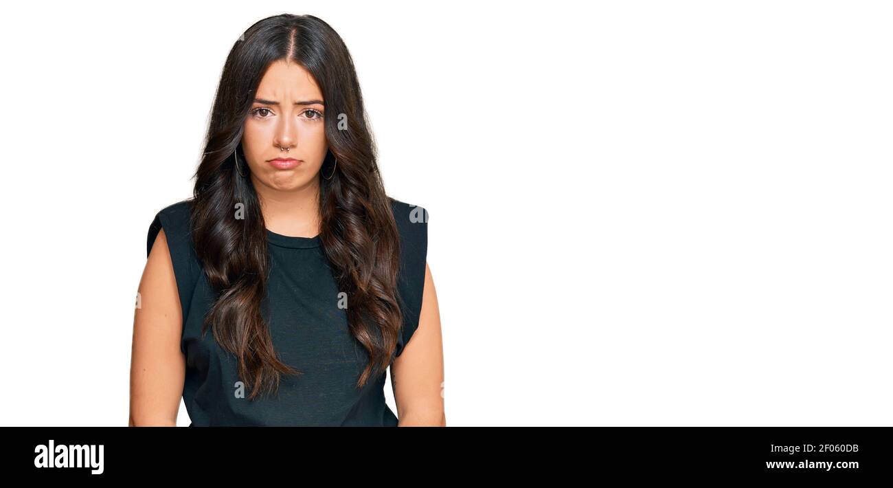 Beautiful brunette young woman wearing black shirt depressed and worry ...