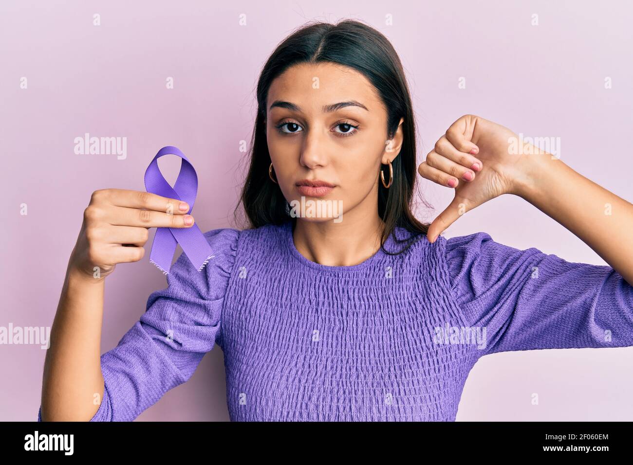 Young hispanic woman holding purple ribbon awareness with angry face ...