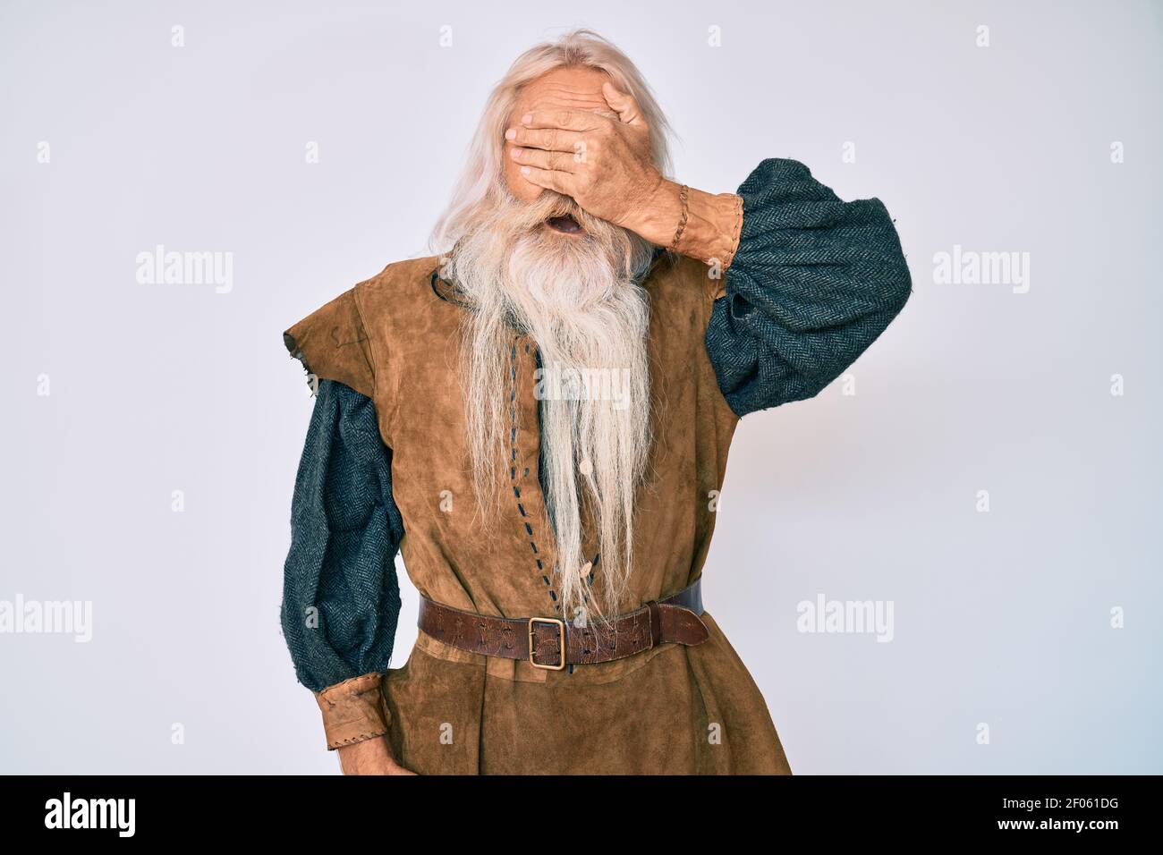 Old senior man with grey hair and long beard wearing viking traditional ...