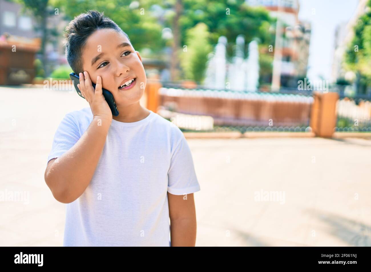 Adorable boy smiling happy talking on the smartphone at street of city ...