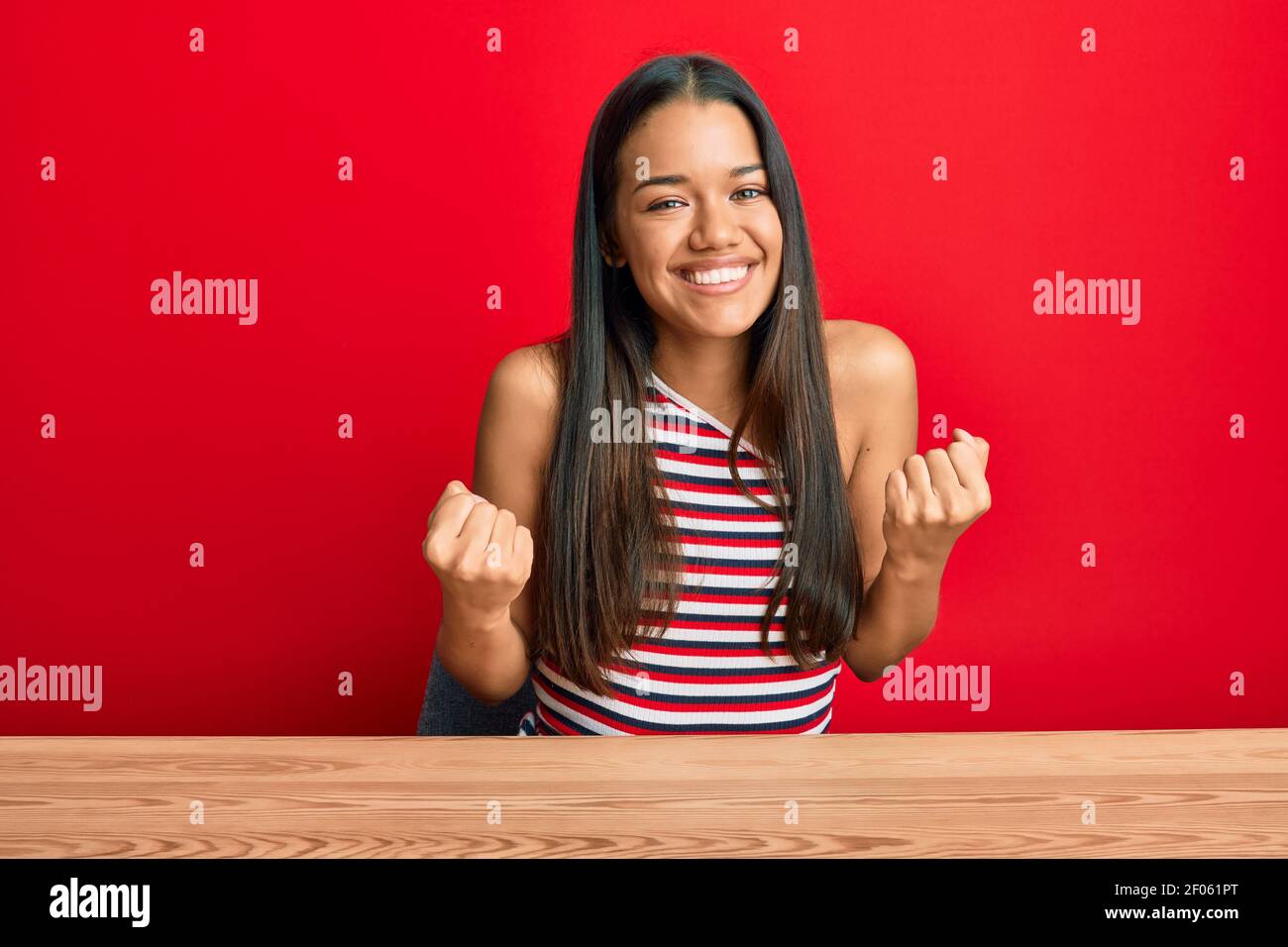 Beautiful hispanic woman wearing casual clothes sitting on the table ...