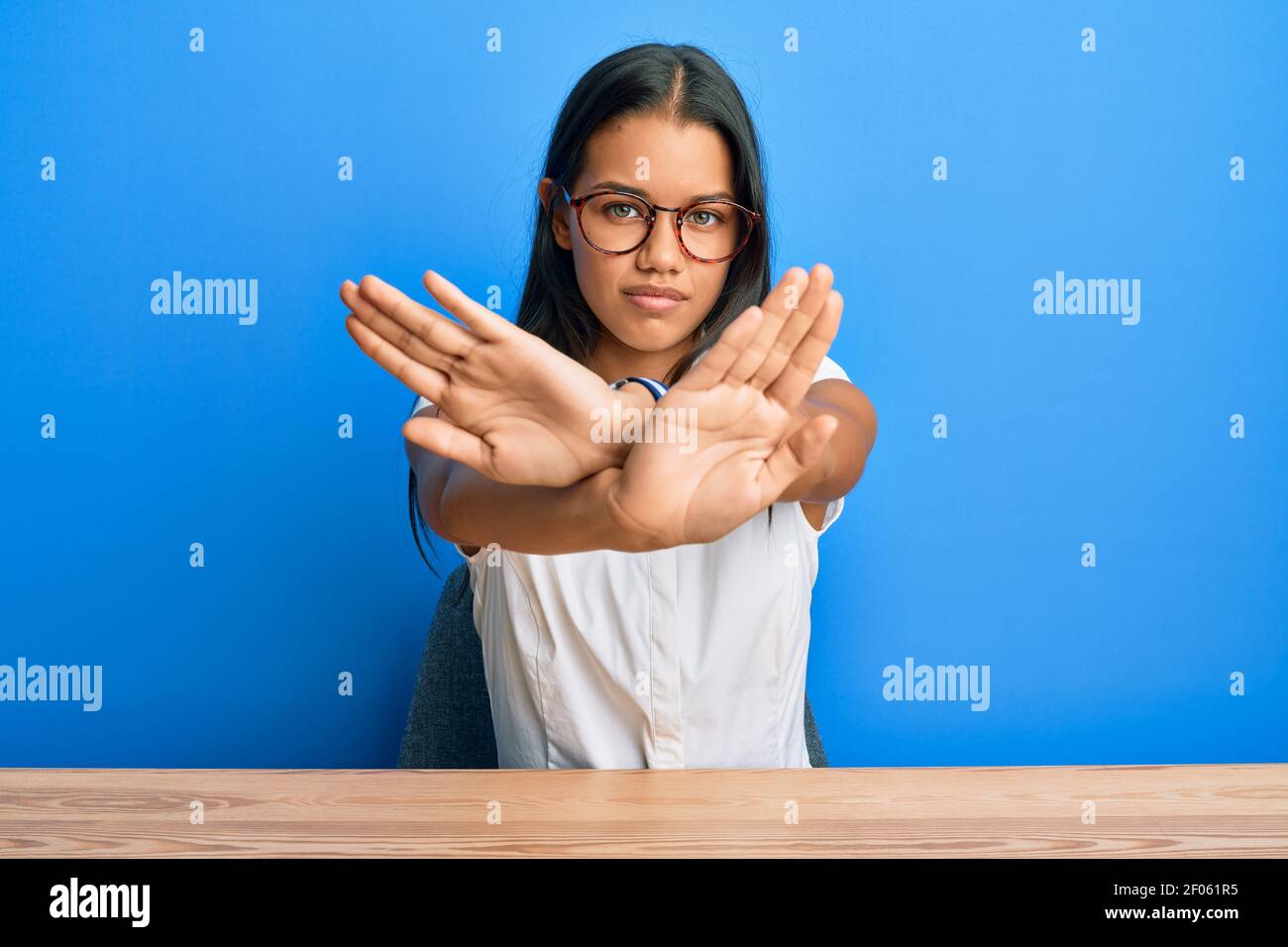 Beautiful hispanic woman wearing casual clothes sitting on the table ...