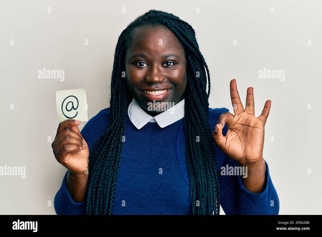 Young black woman with braids holding email symbol on paper doing ok ...