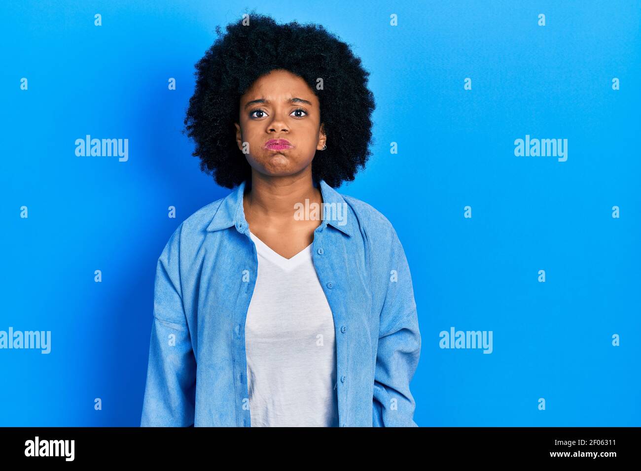 Young african american woman wearing casual clothes puffing cheeks with ...